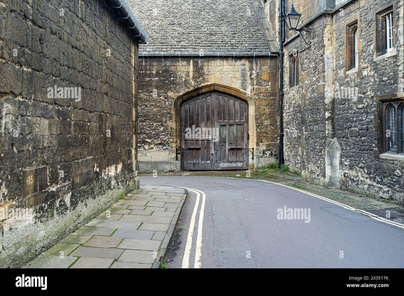 Old medieval alley in England with stone building and wooden gate Stock ...