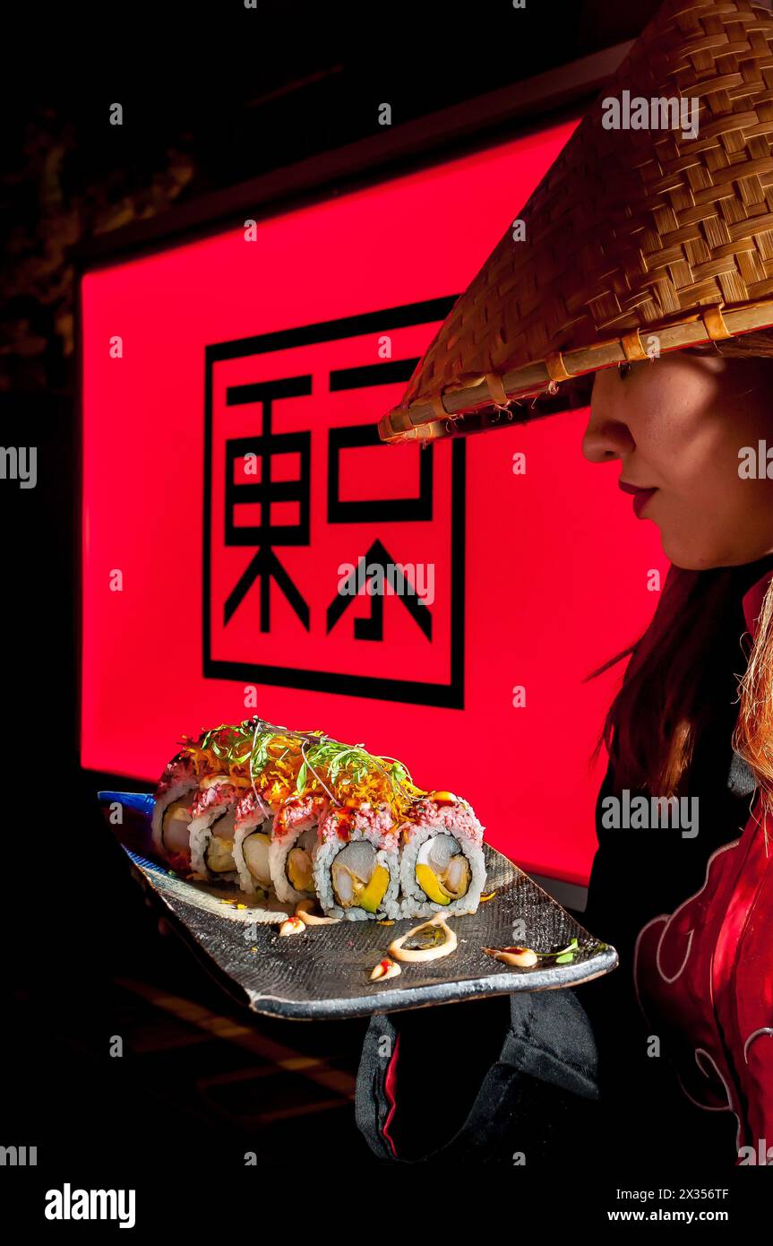 Redhead girl in japanese disguise and conical hat serving sushi with ...