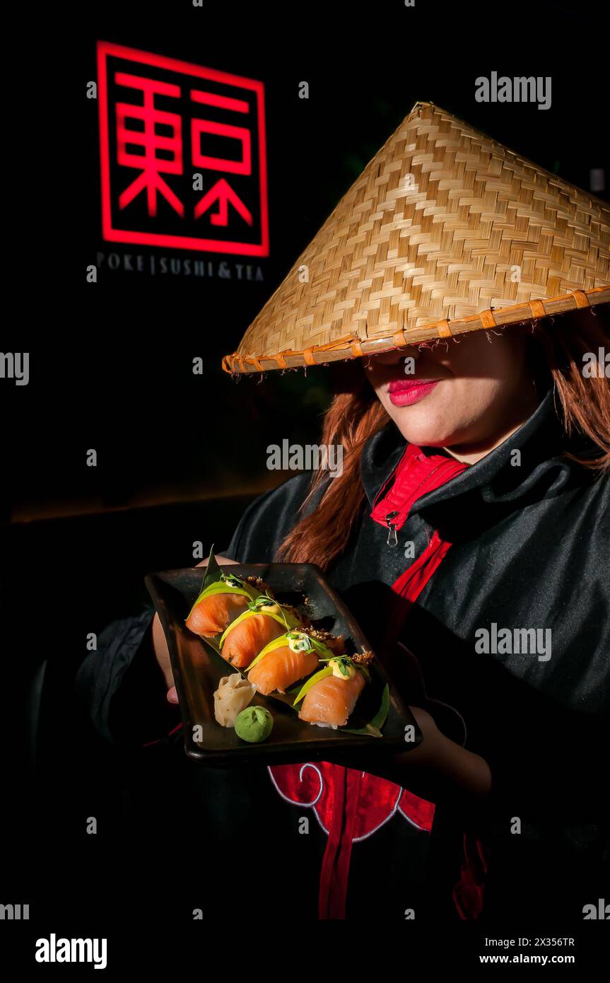Redhead girl in japanese disguise and conical hat serving salmon sushi ...
