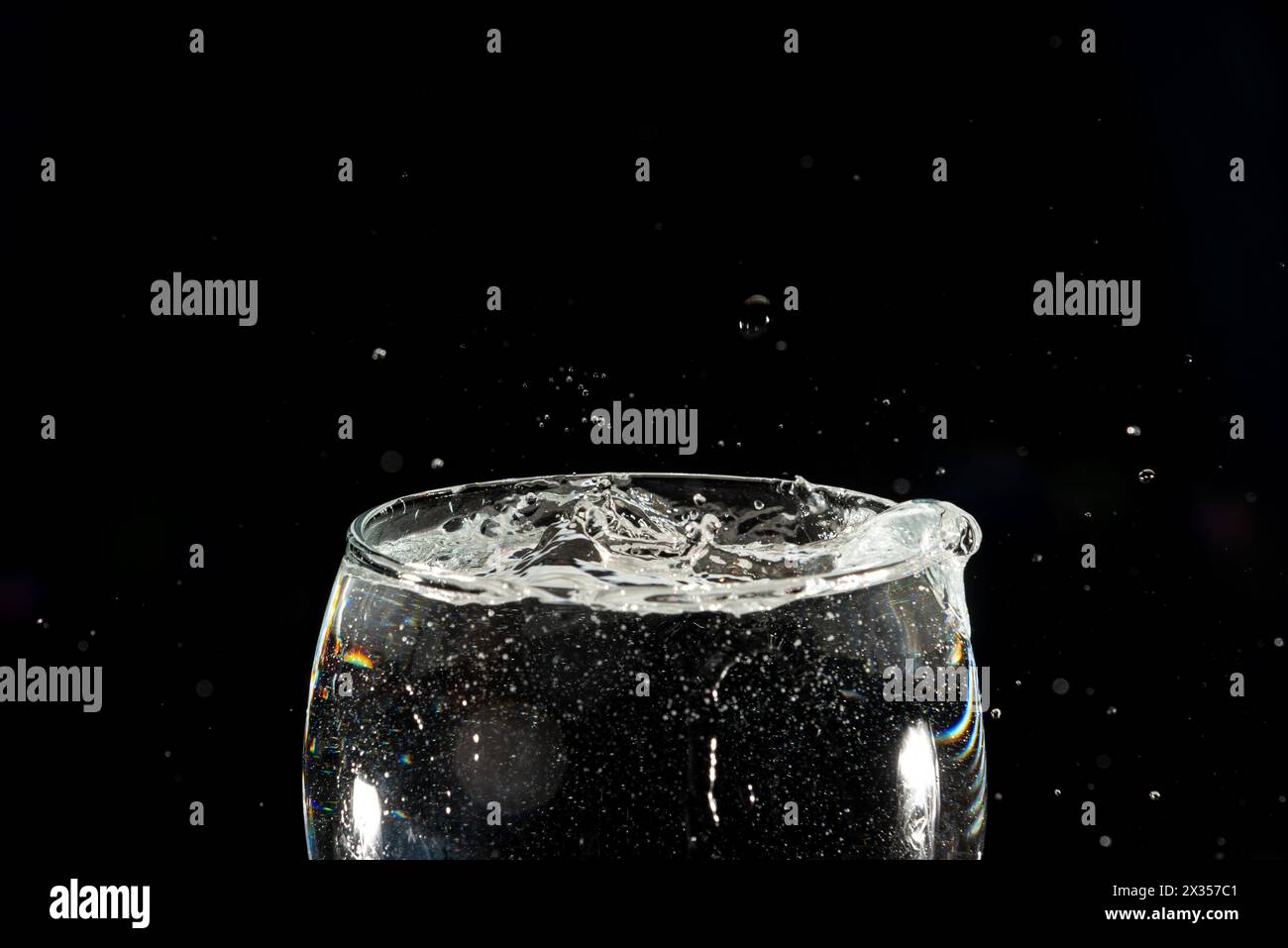 Splashing water drops in a full glass goblet. Splash Effect. Isolated ...