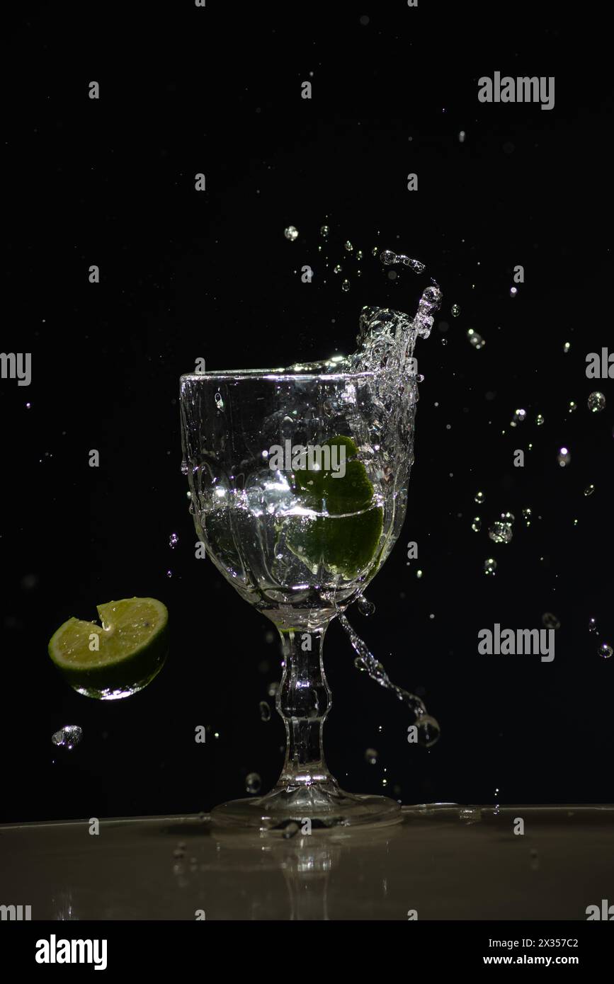 Splashes coming out of a glass cup with clear water caused by a slice ...