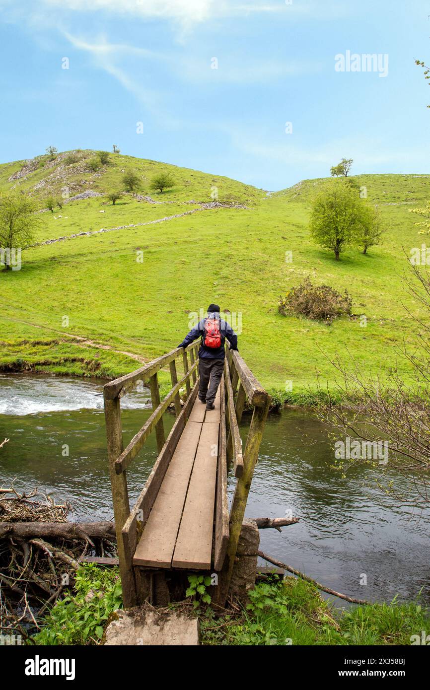 Man walking backpacking on wooden footbridge over the River Dove in ...