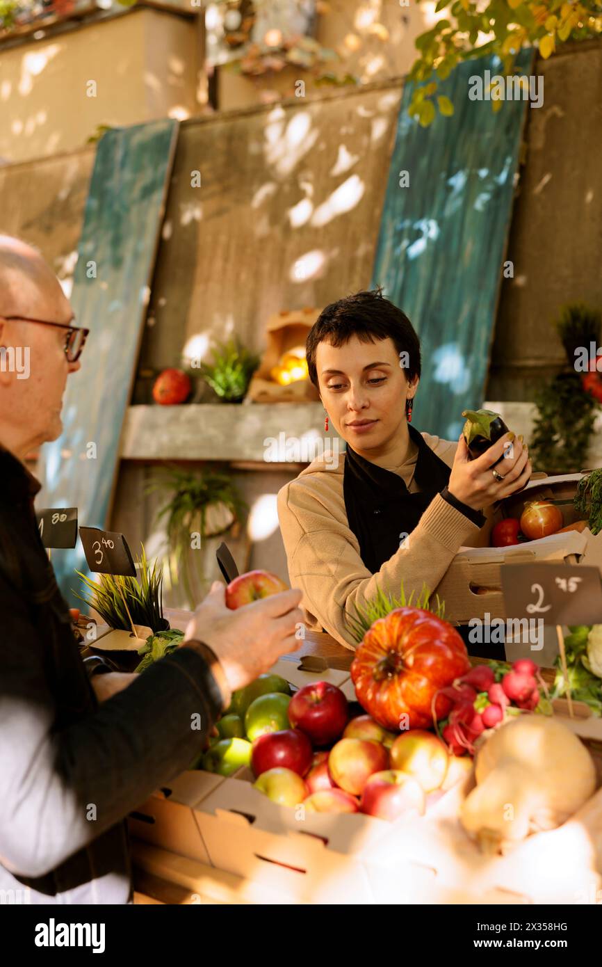 Female vendor arranging organic produce on greenmarket stand while ...