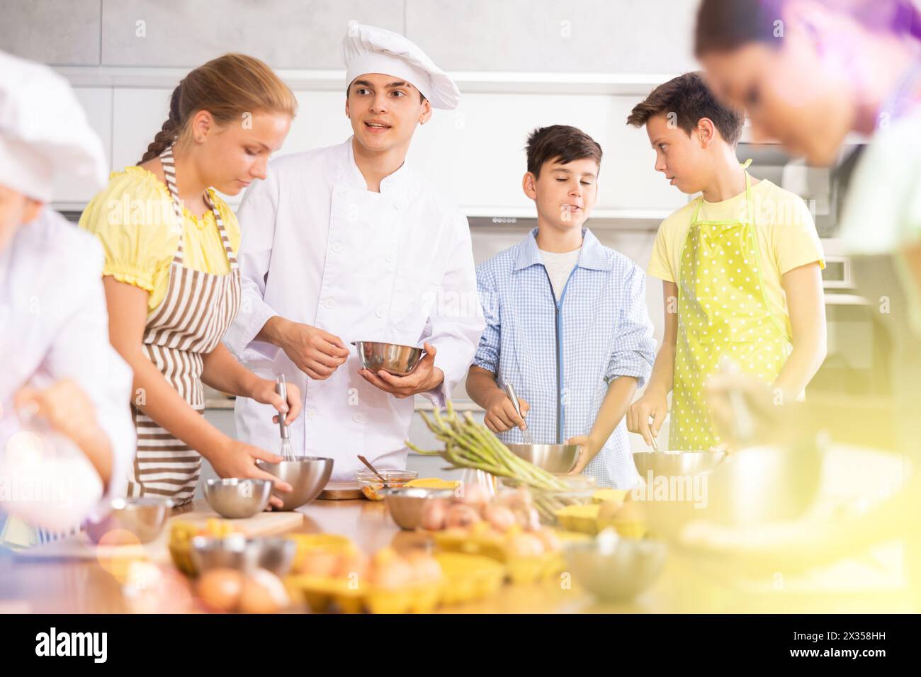 In cooking class, guy cook with bowl in hands tells children ...