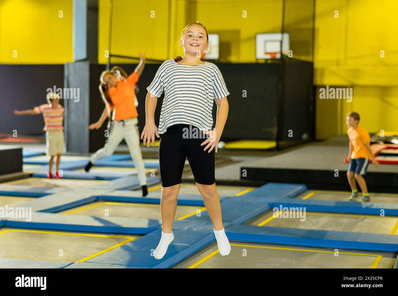 Happy cute little girl jumping on trampoline indoors Stock Photo - Alamy