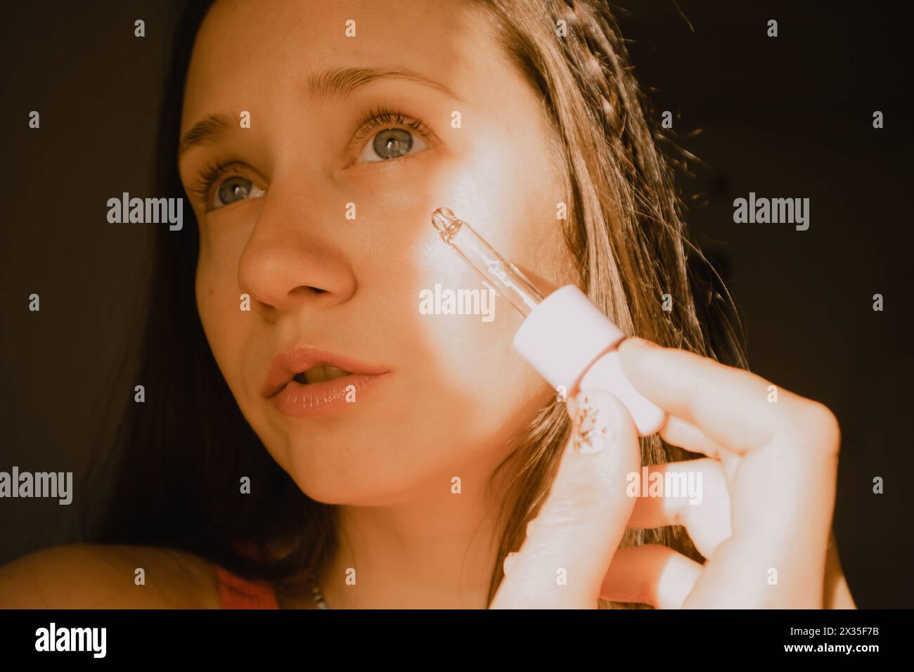 Beautiful white European baby face young woman applying serum from an ...