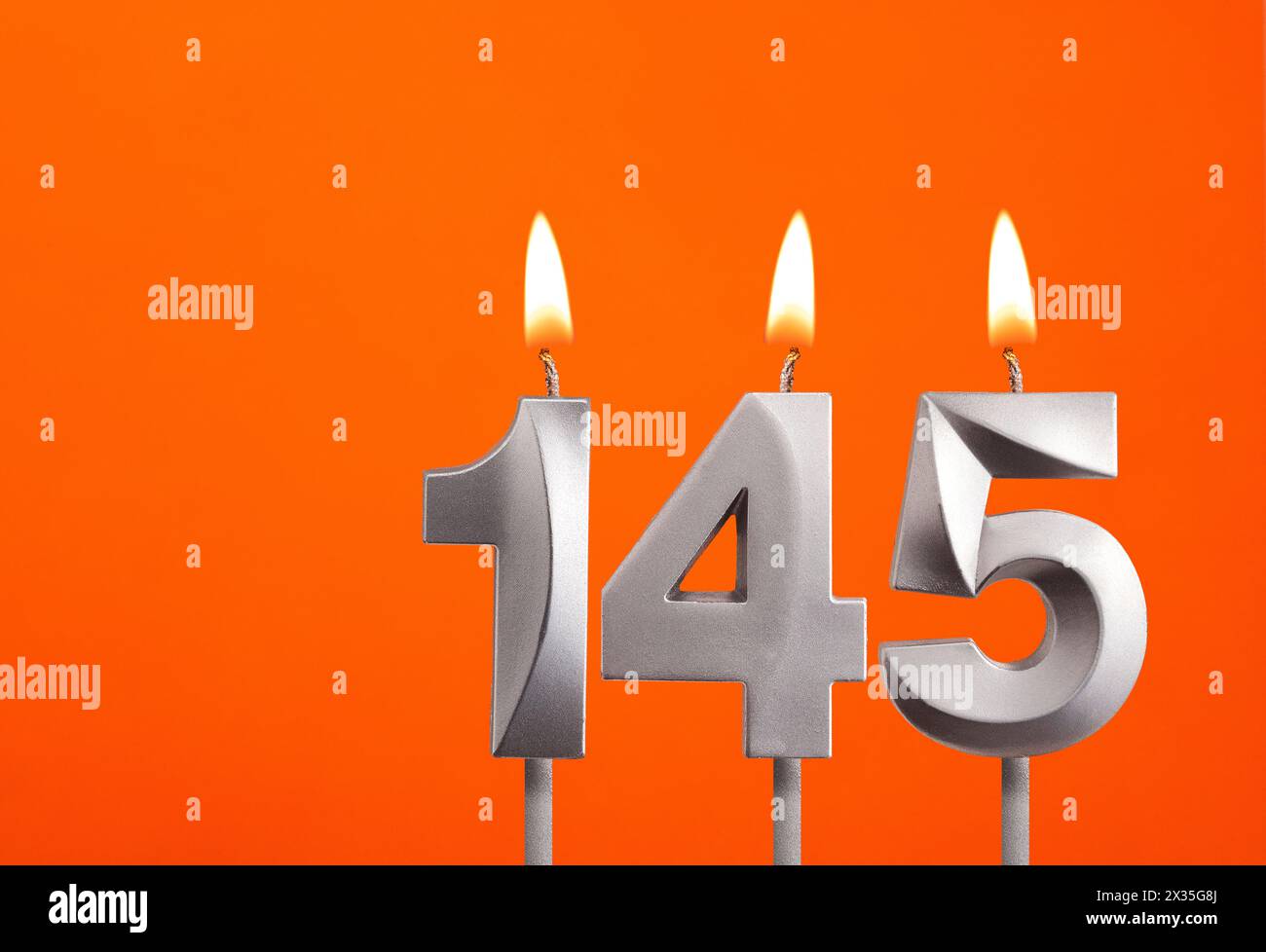 Candle number 145 - Birthday in orange background Stock Photo - Alamy