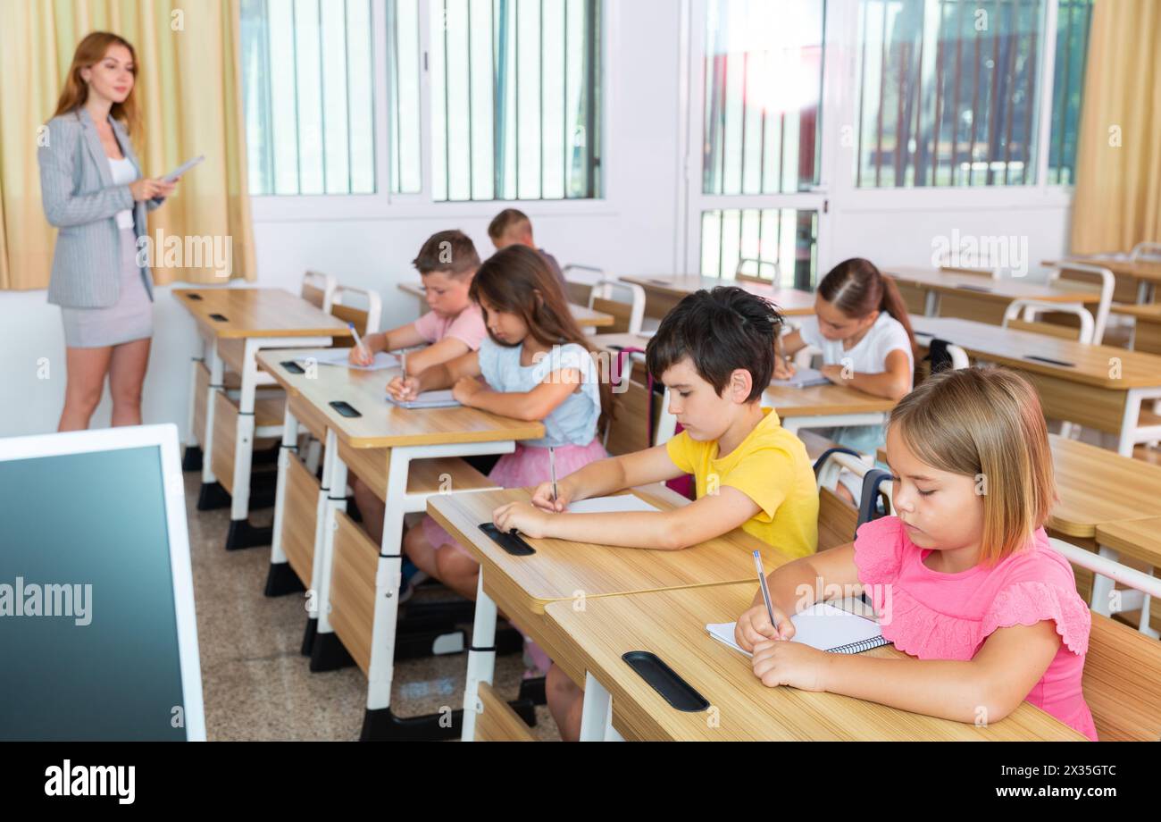 Group of school kids and teacher during lesson in classroom Stock Photo ...
