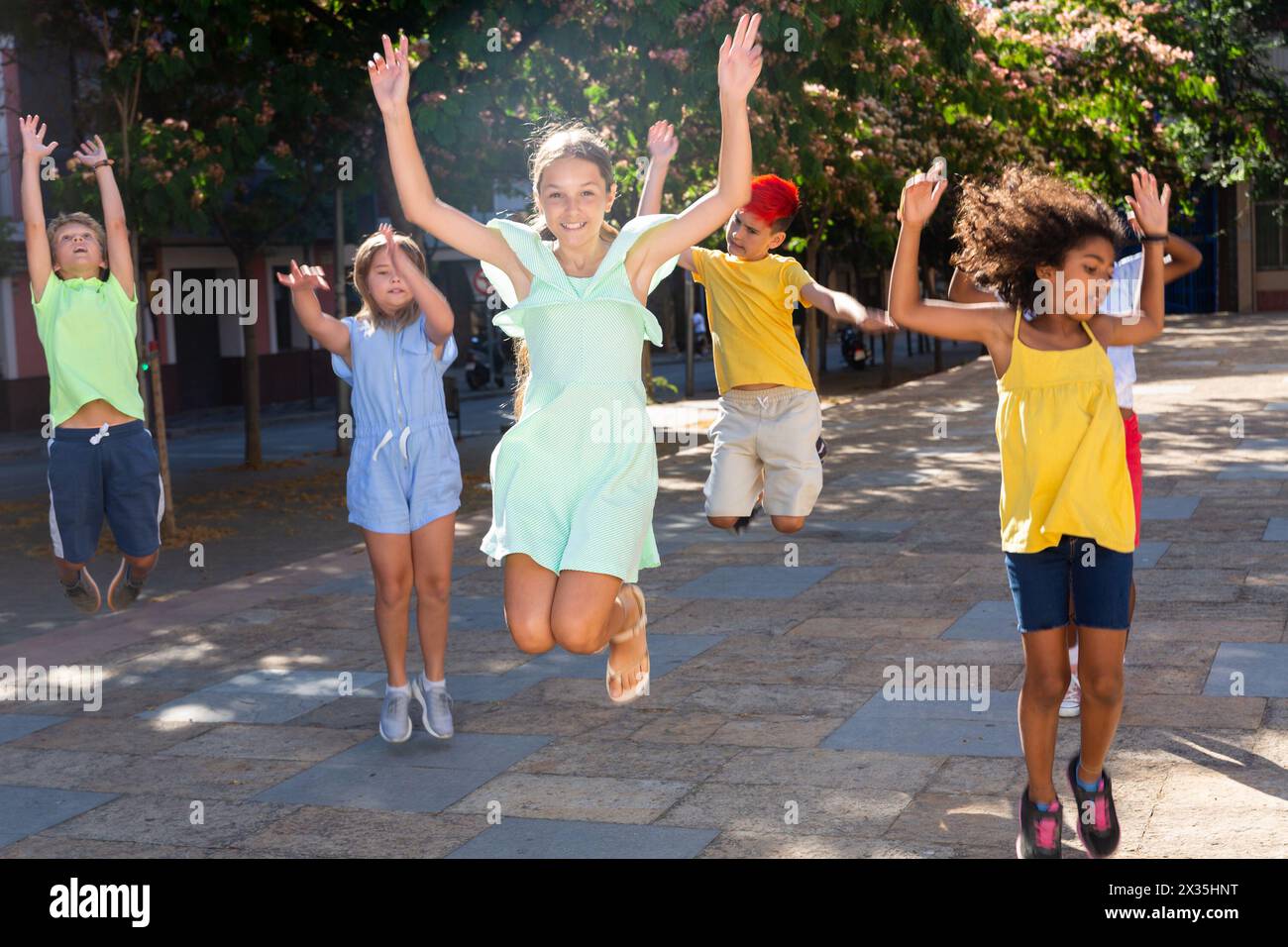 Happy tween girl jumping with friends on city street Stock Photo - Alamy