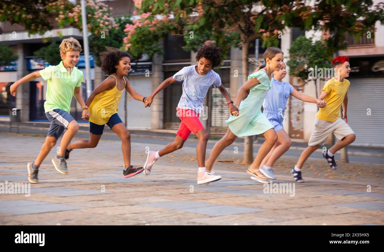 Happy tween friends running together on summer city street Stock Photo ...