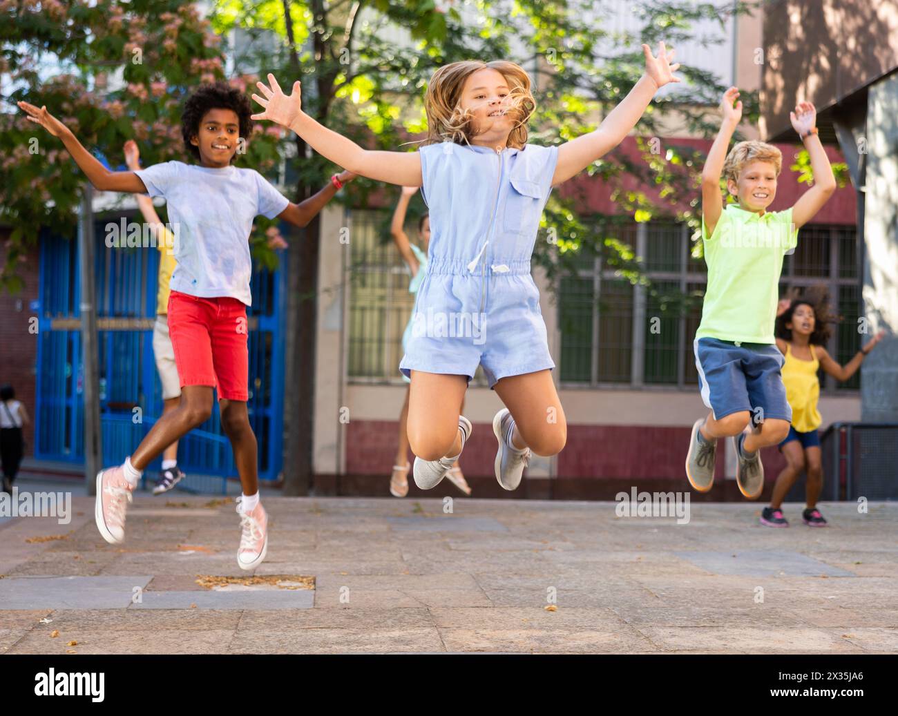 Happy tween girl jumping with friends on city street Stock Photo - Alamy