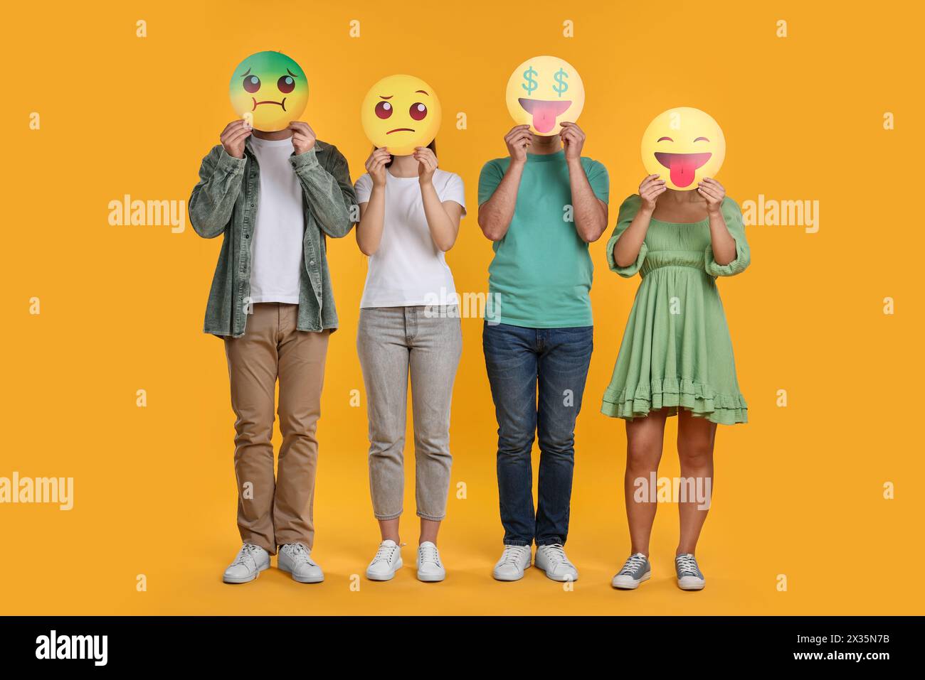 People covering faces with emoticons on yellow background Stock Photo ...