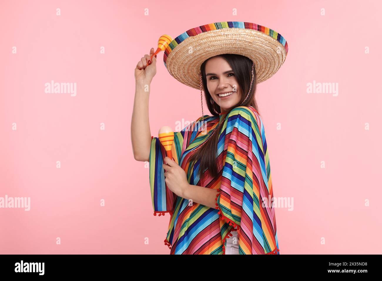 Young woman in Mexican sombrero hat and poncho dancing with maracas on ...
