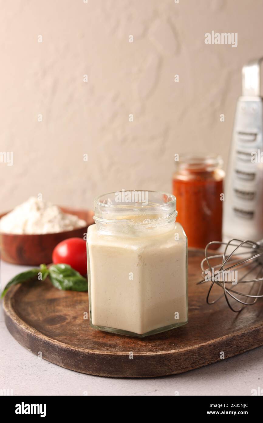 Pizza dough starter in glass jar and products on gray table Stock Photo ...