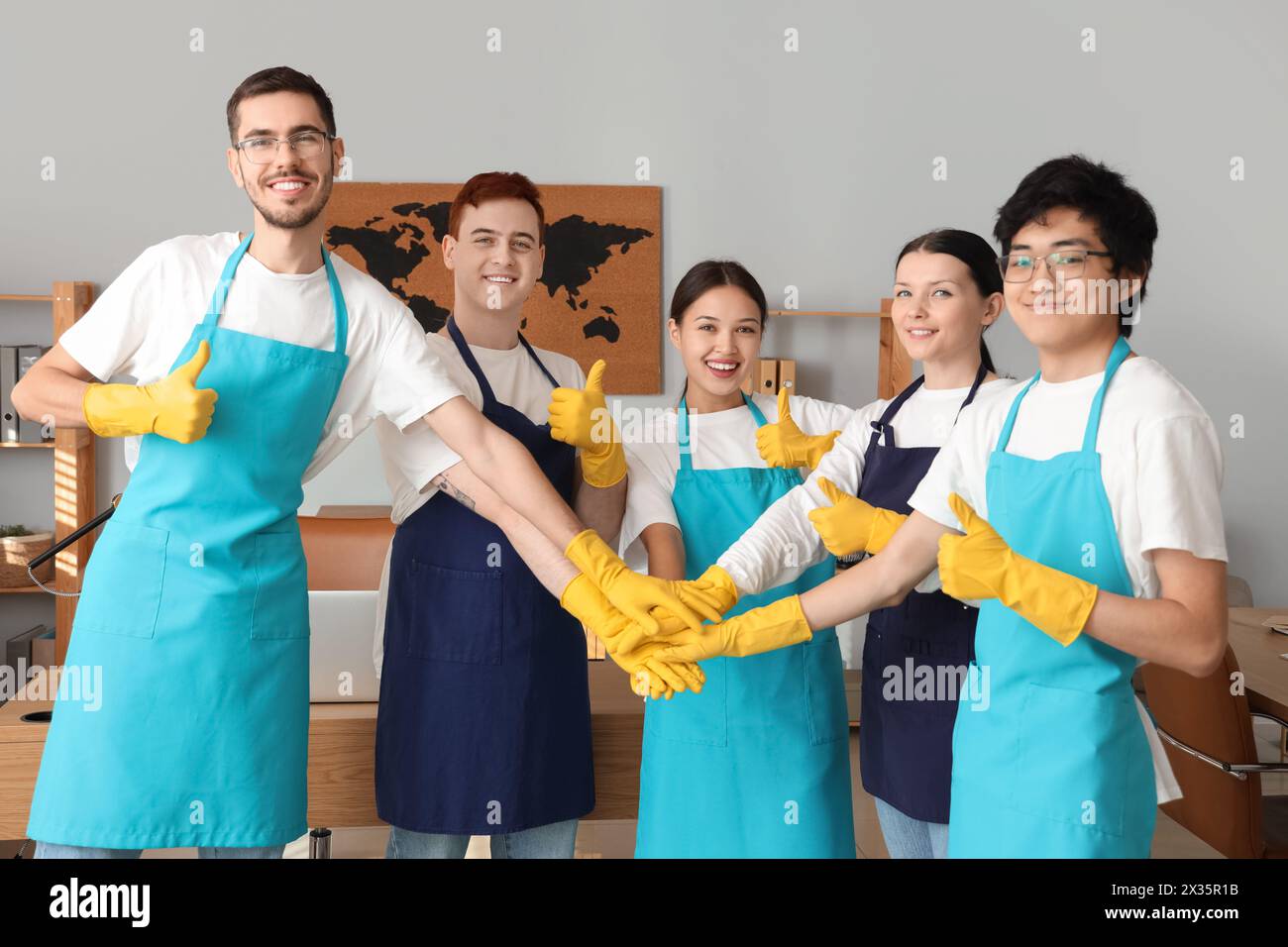 Group of young janitors putting hands together in office Stock Photo ...