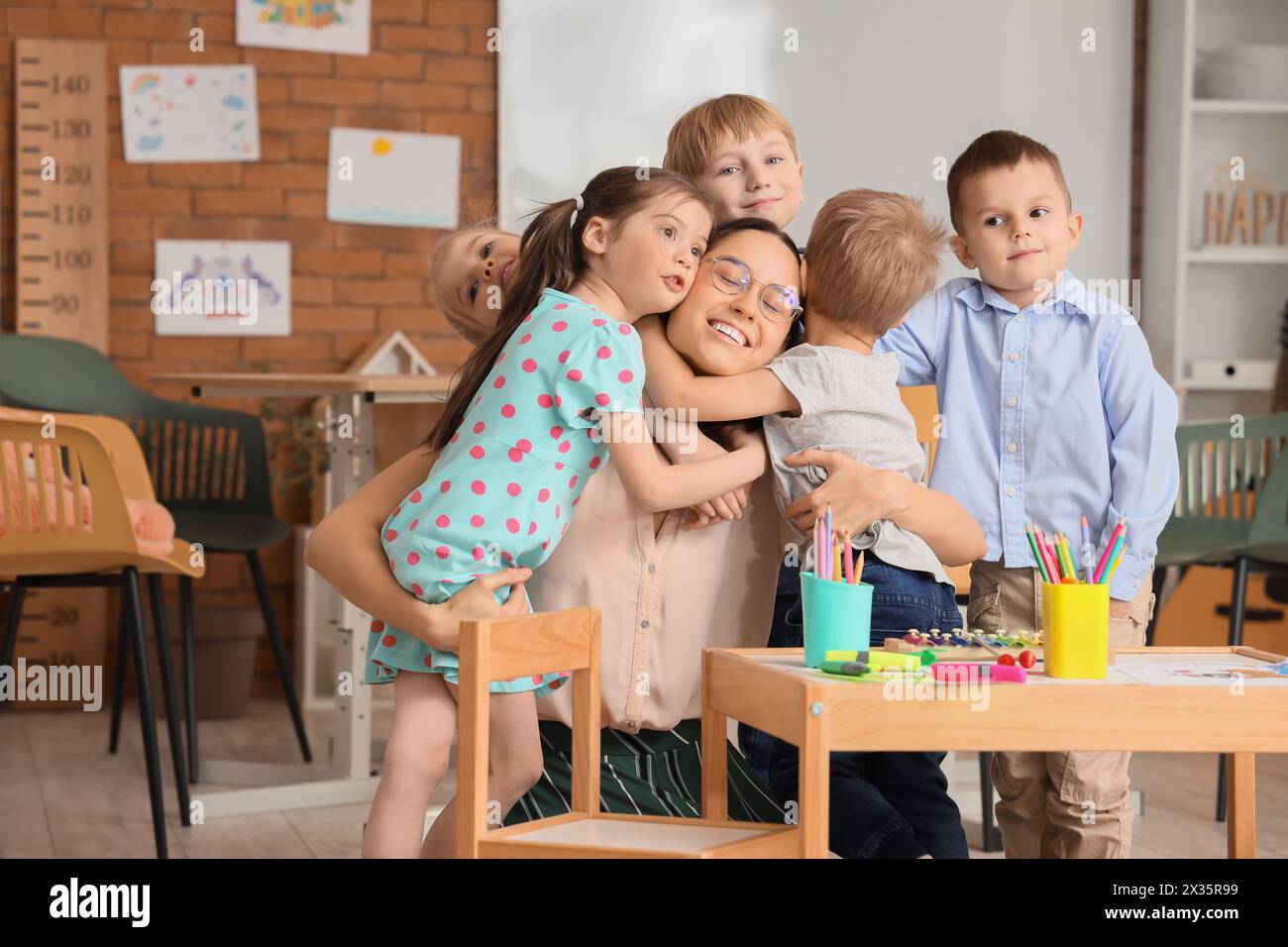 Little children hugging nursery teacher during art lesson in ...