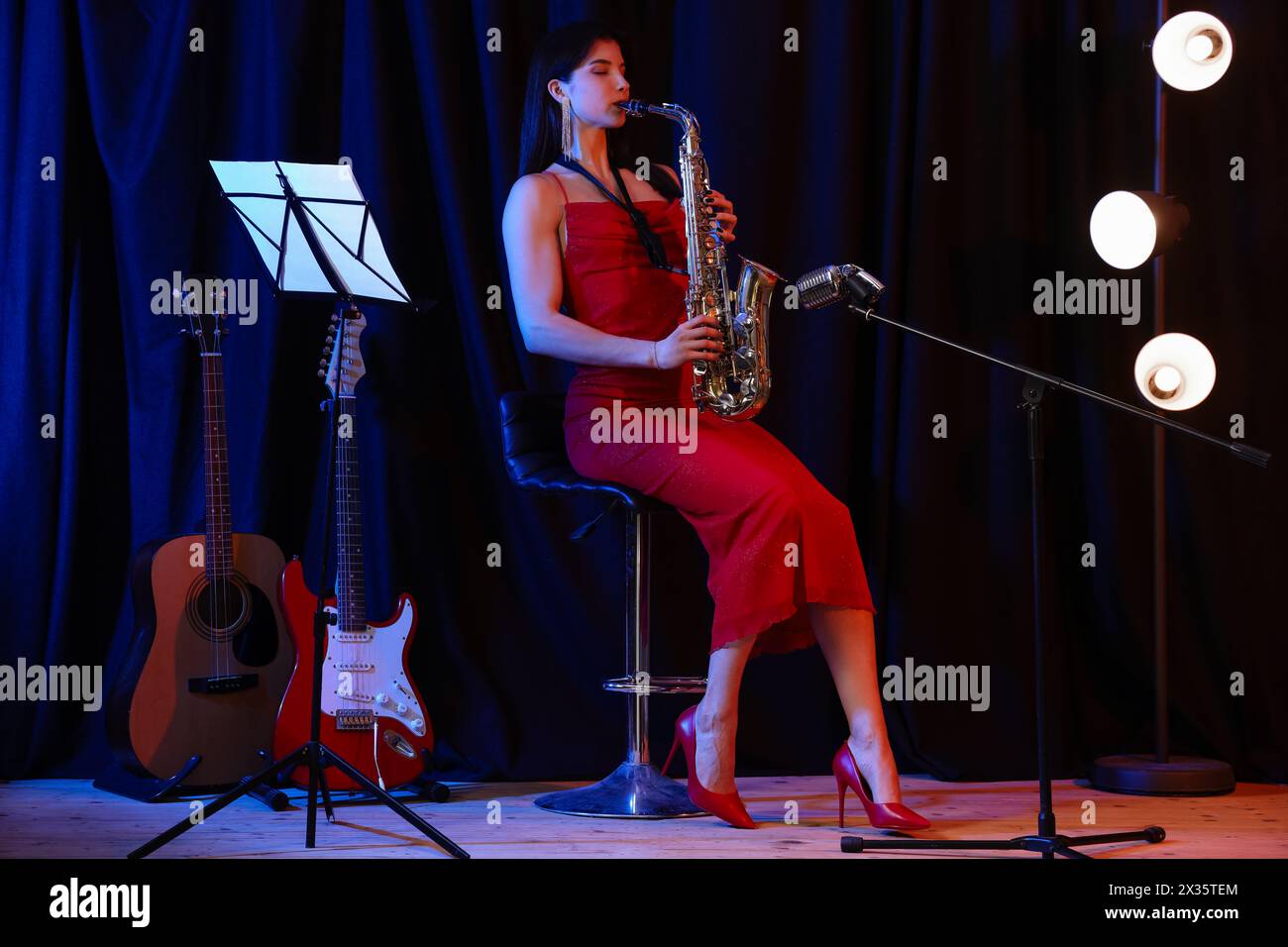 Beautiful woman playing saxophone on stage Stock Photo - Alamy