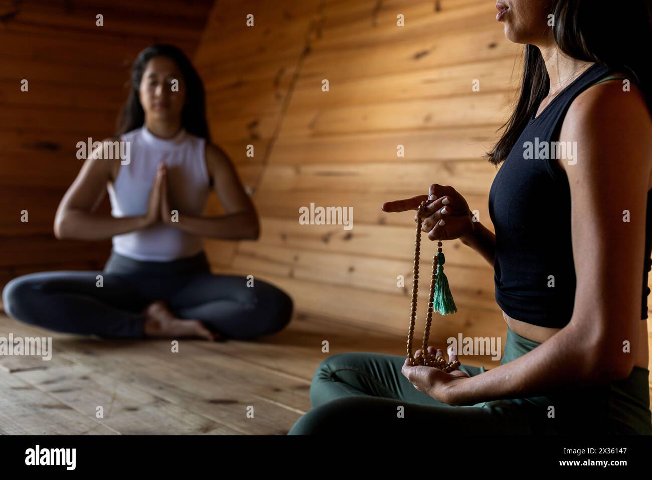 Two young Latin American girls in meditation position with a Japa Mala ...