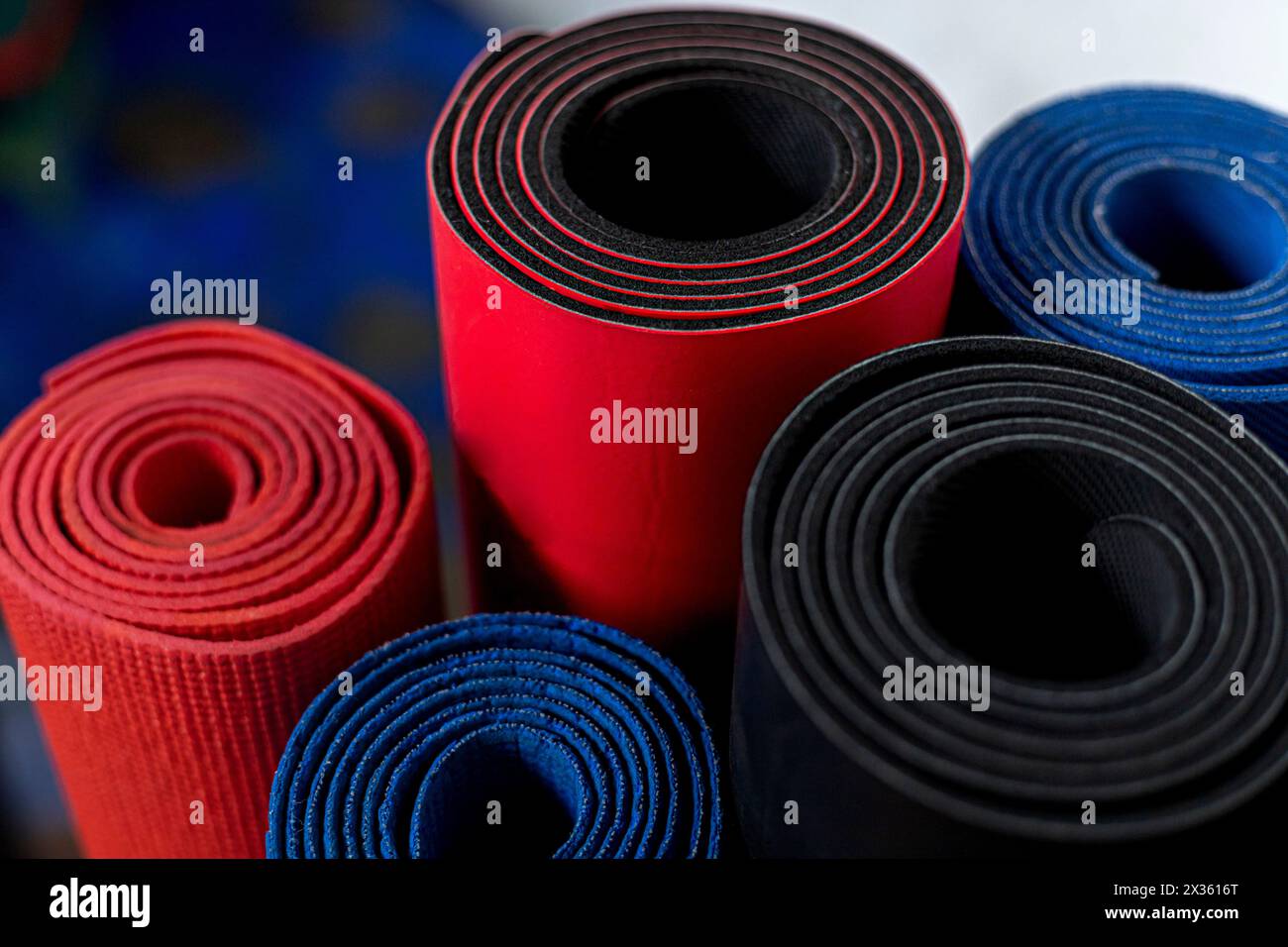 Different types of yoga mats rolled up and standing vertically. Yoga ...