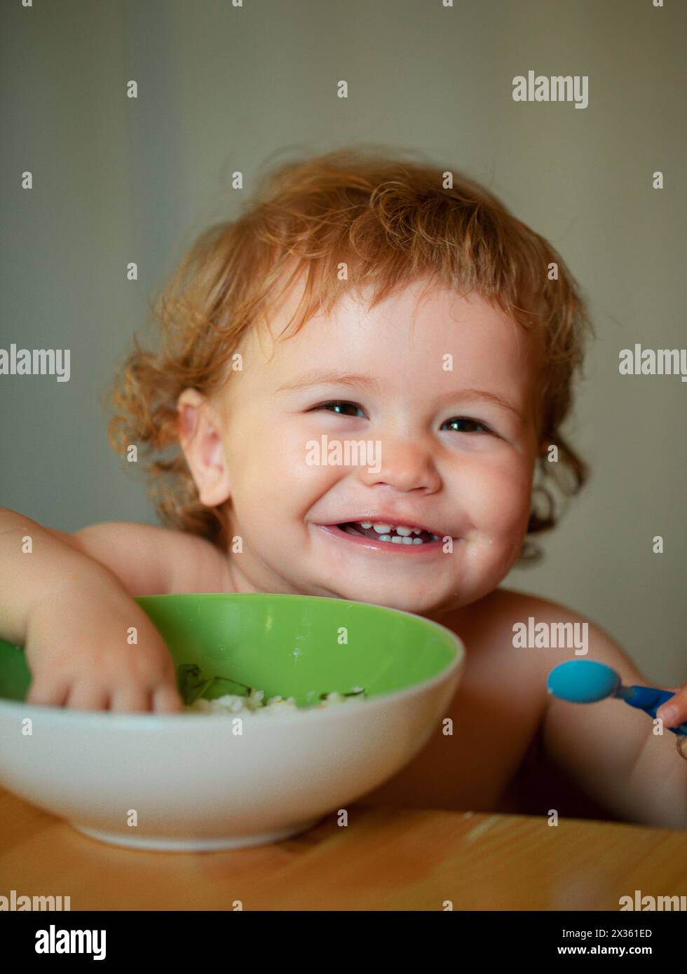 Launching child eat. Happy baby eating himself with a spoon. Smiling ...