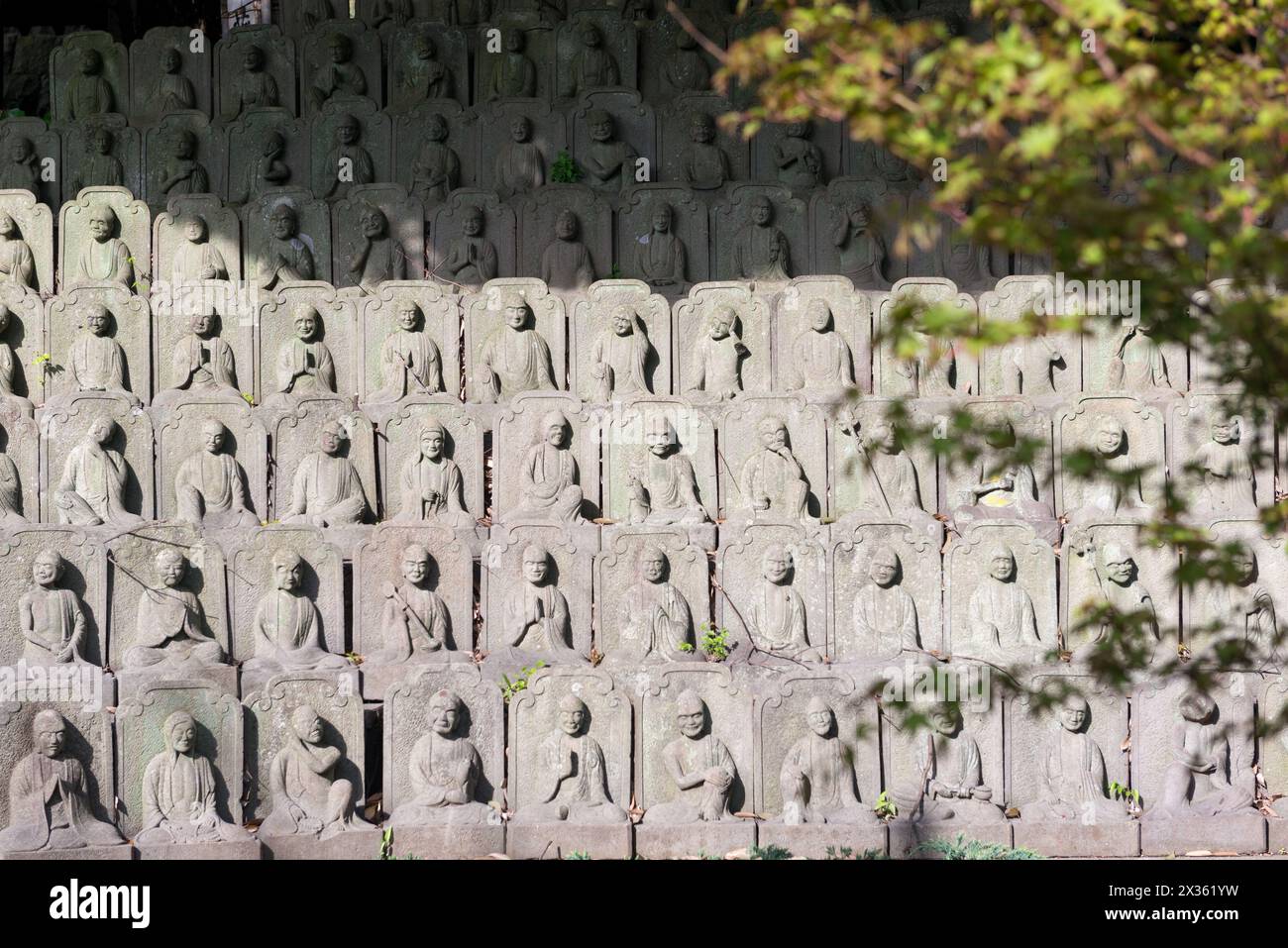 A wall of statues of people, some of which are of Buddha. The wall is ...