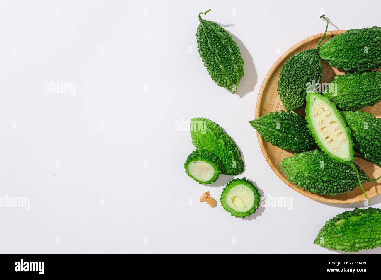 On a wooden dish and white background, fresh green bitter melons ...