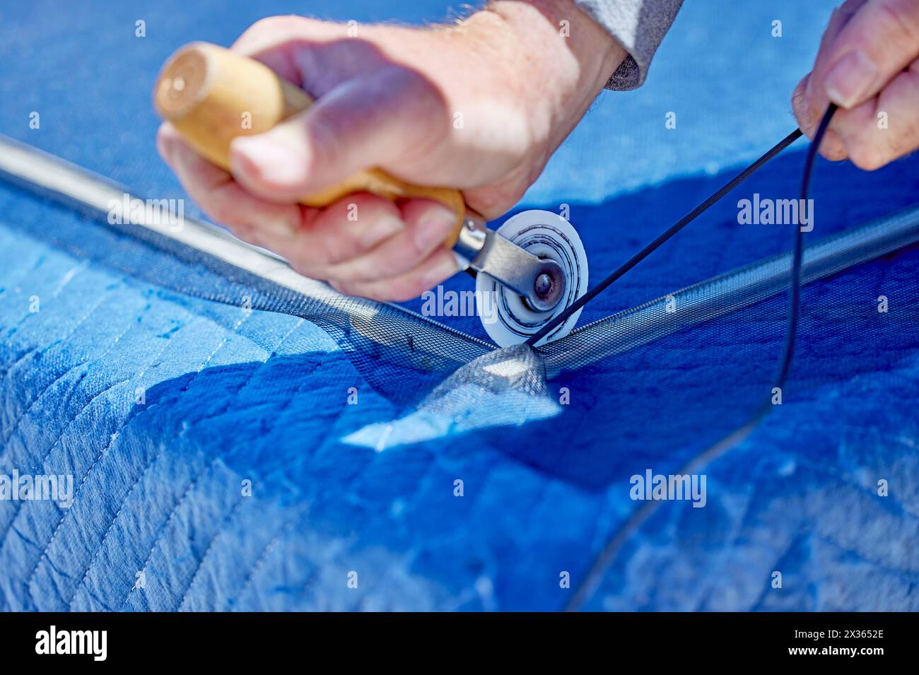 Close up the hands of a man holding a screen roller replacing a window ...