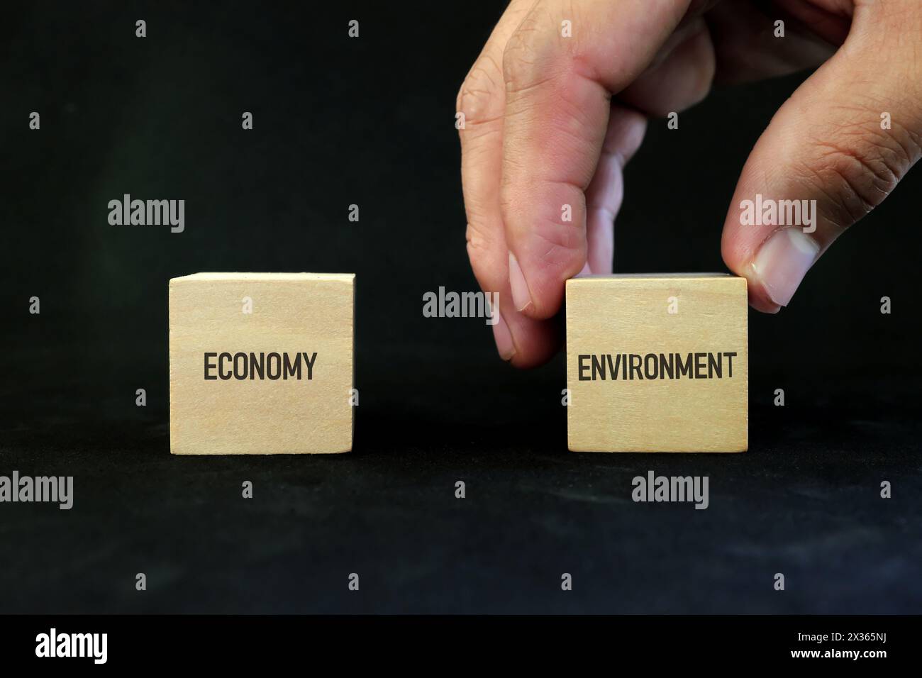 Economy versus environment concept. Human hand picking up wooden block ...
