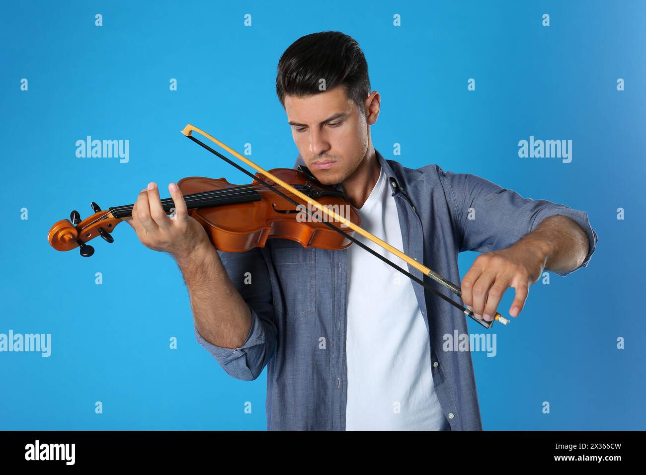 Man playing violin on light blue background Stock Photo - Alamy
