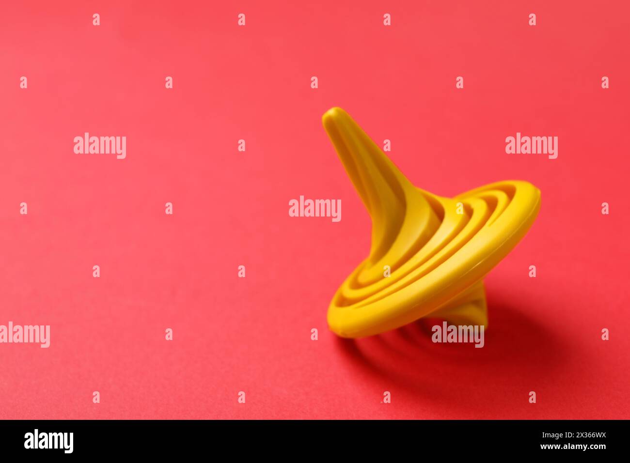 One yellow spinning top on red background, closeup. Space for text ...