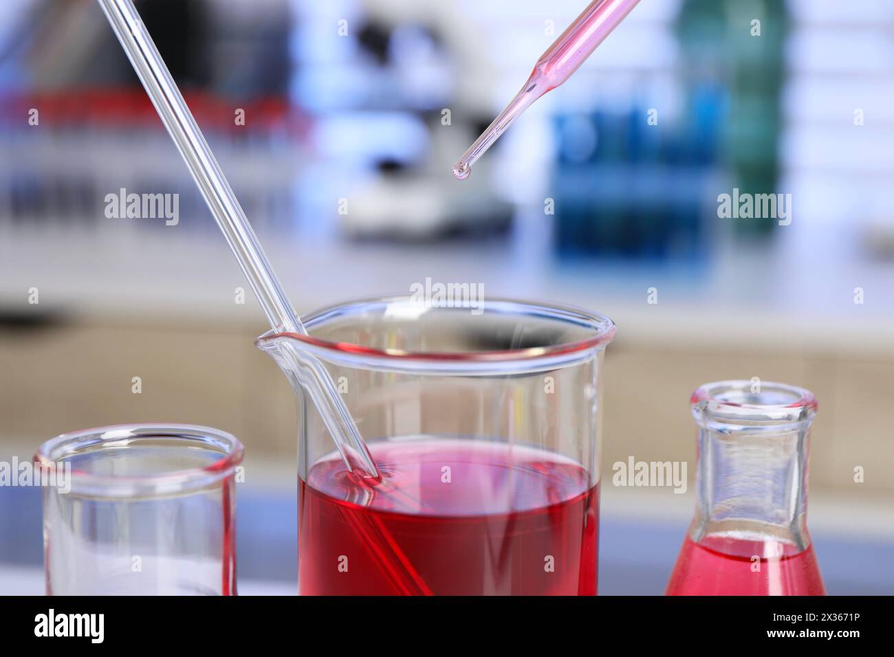 Laboratory analysis. Dripping red liquid into beaker on table, closeup ...