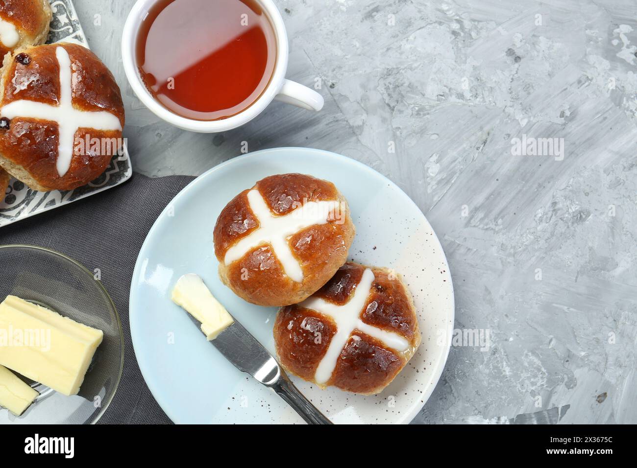Tasty hot cross buns served on gray textured table, flat lay. Space for ...
