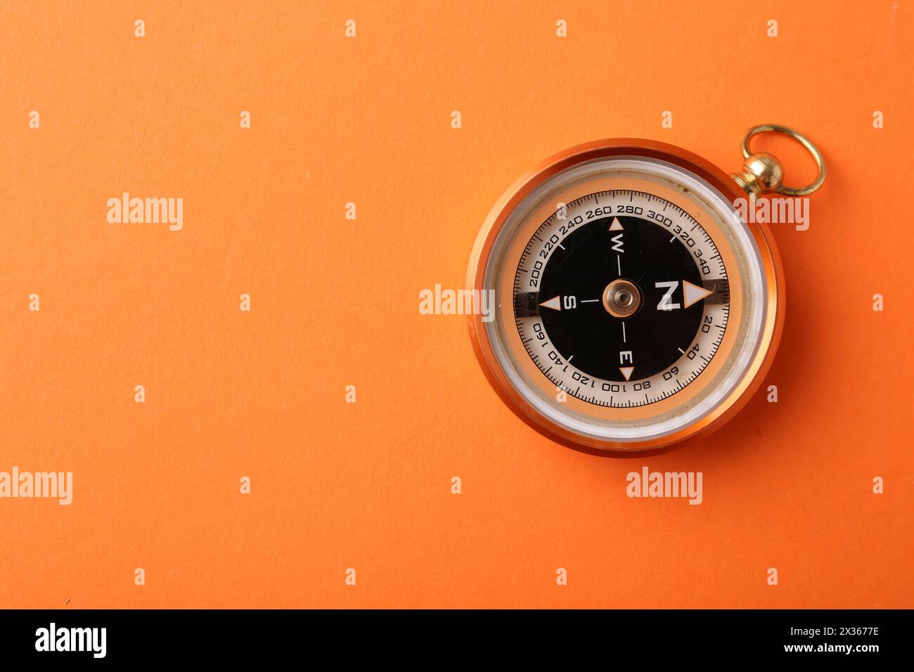 One compass on orange background, top view. Space for text Stock Photo ...