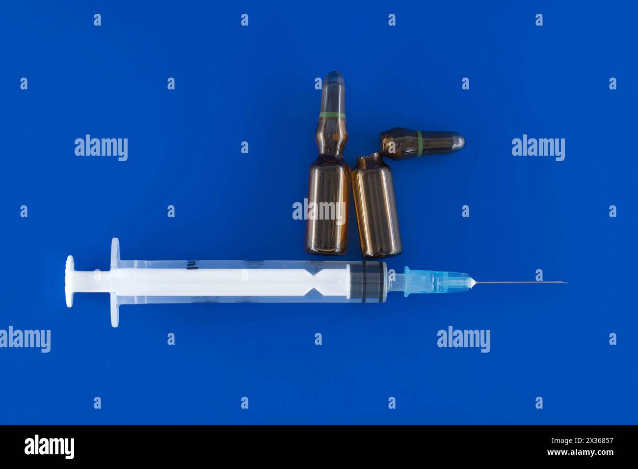 Needle, syringe and two brown vaccine ampules appearing ready for use ...