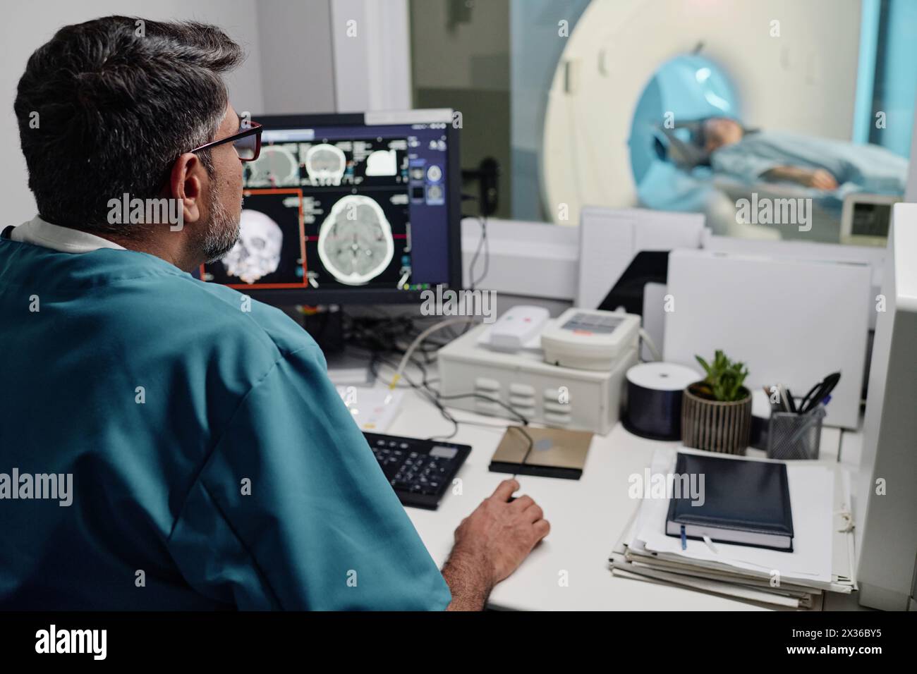 Selective focus over-the-shoulder shot of male radiographer controlling ...