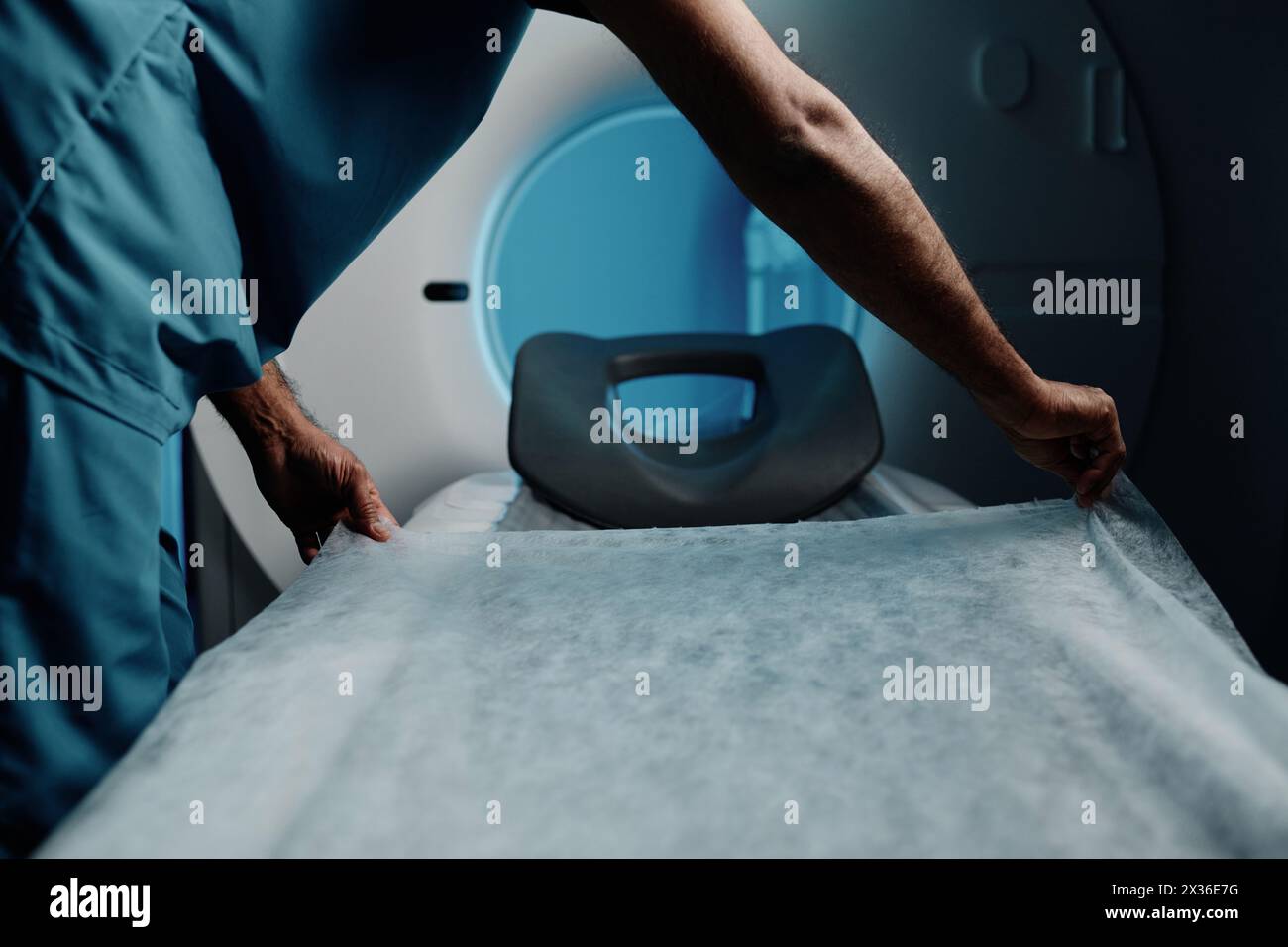 Unrecognizable male radiographer preparing CT scanner bed covering it ...