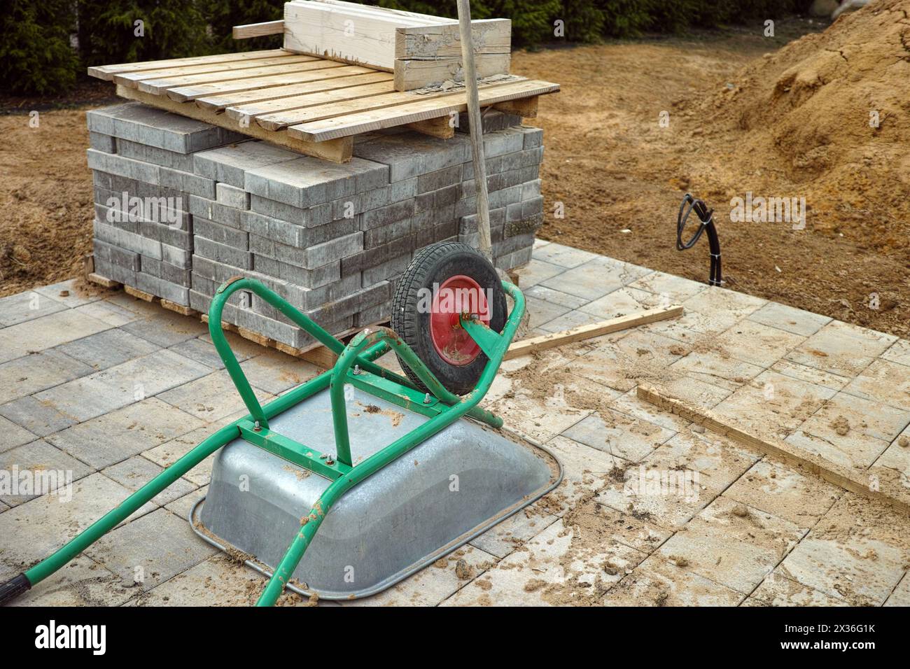 a tipped over trolley and a stack of tiles next to the pile of sand ...