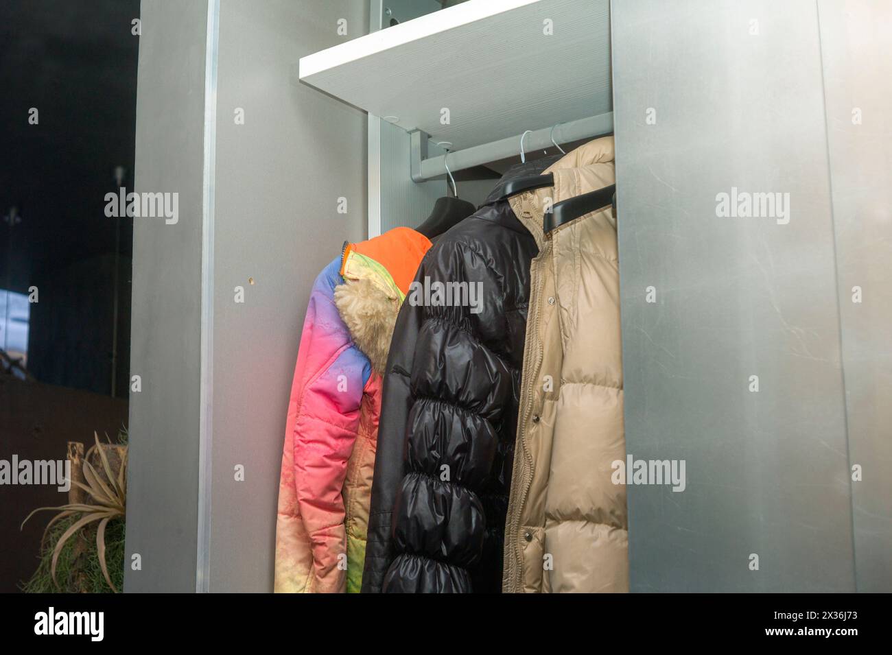 open sliding door of a wardrobe with hanging winter jackets, indoor ...