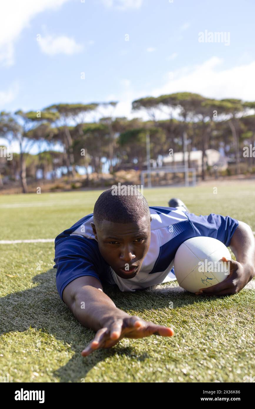 An African American young male rugby player scoring a try on a grass ...