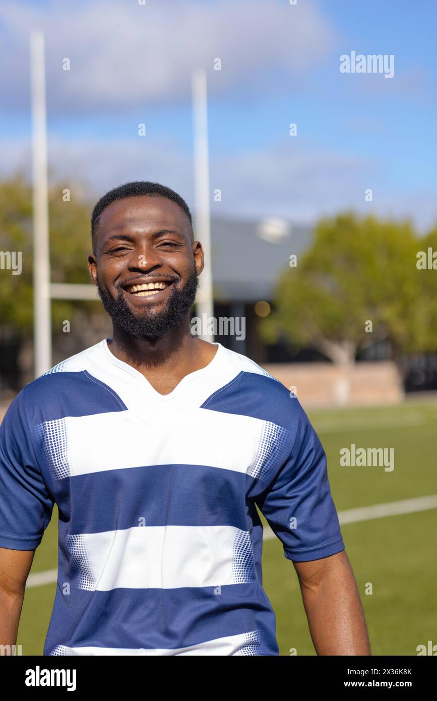 African American young male athlete standing on a rugby field, smiling ...