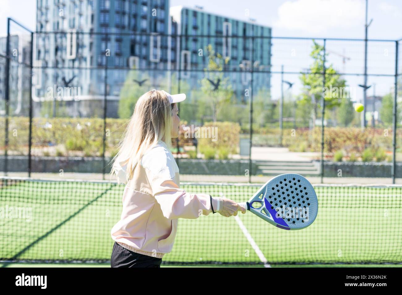 Young sporty woman performing basic strokes during paddle tennis group ...