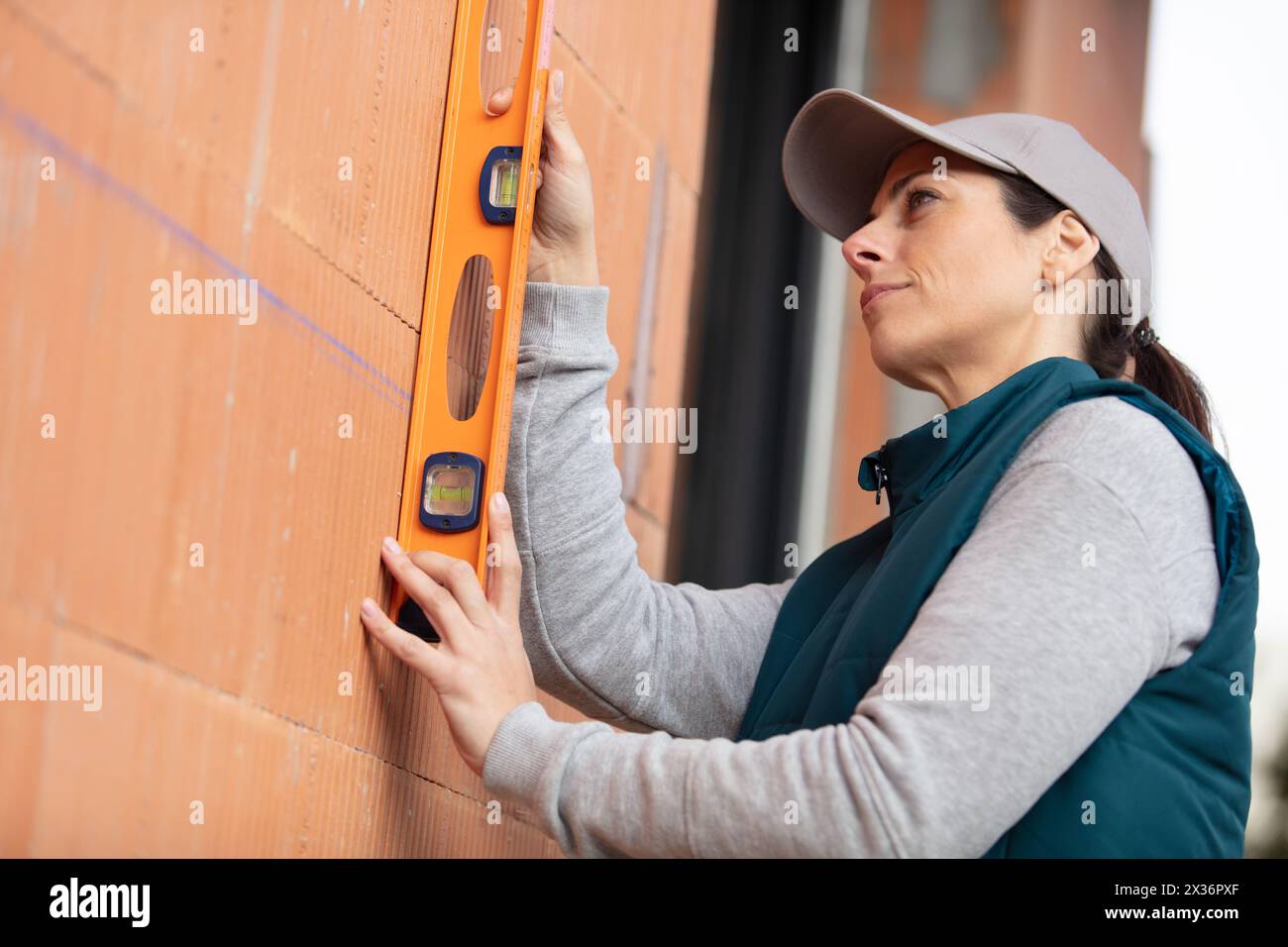 woman bricklayer holding a spirit level on a brick wall Stock Photo - Alamy