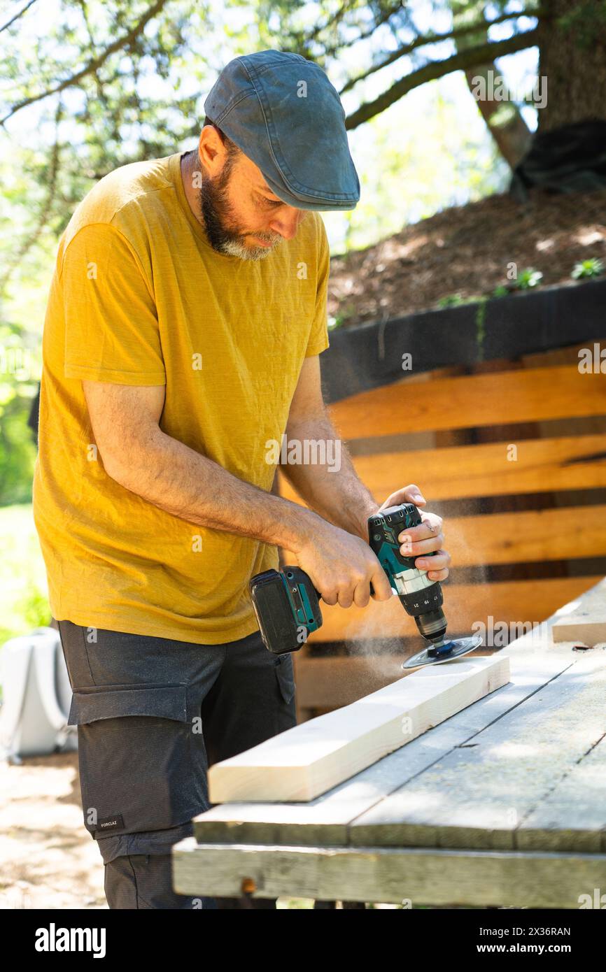 Middle-aged Caucasian man working sanding wood with an electric sander ...