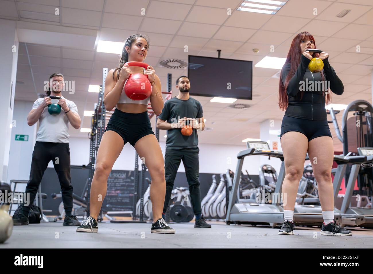 In a dynamic fitness class, participants perform kettlebell squats ...