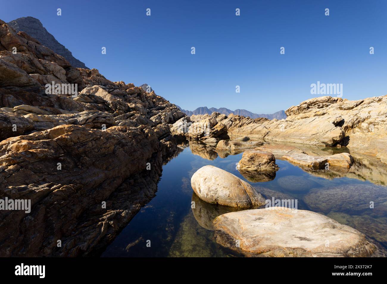 Rugged rocks surround calm water reflecting blue sky, copy space Stock ...