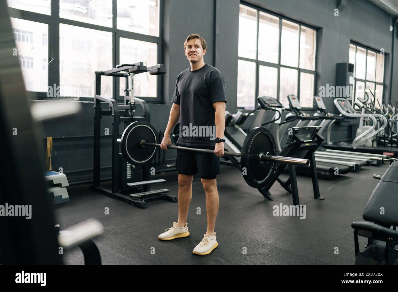 Full length portrait of cheerful handsome sportsman training biceps ...
