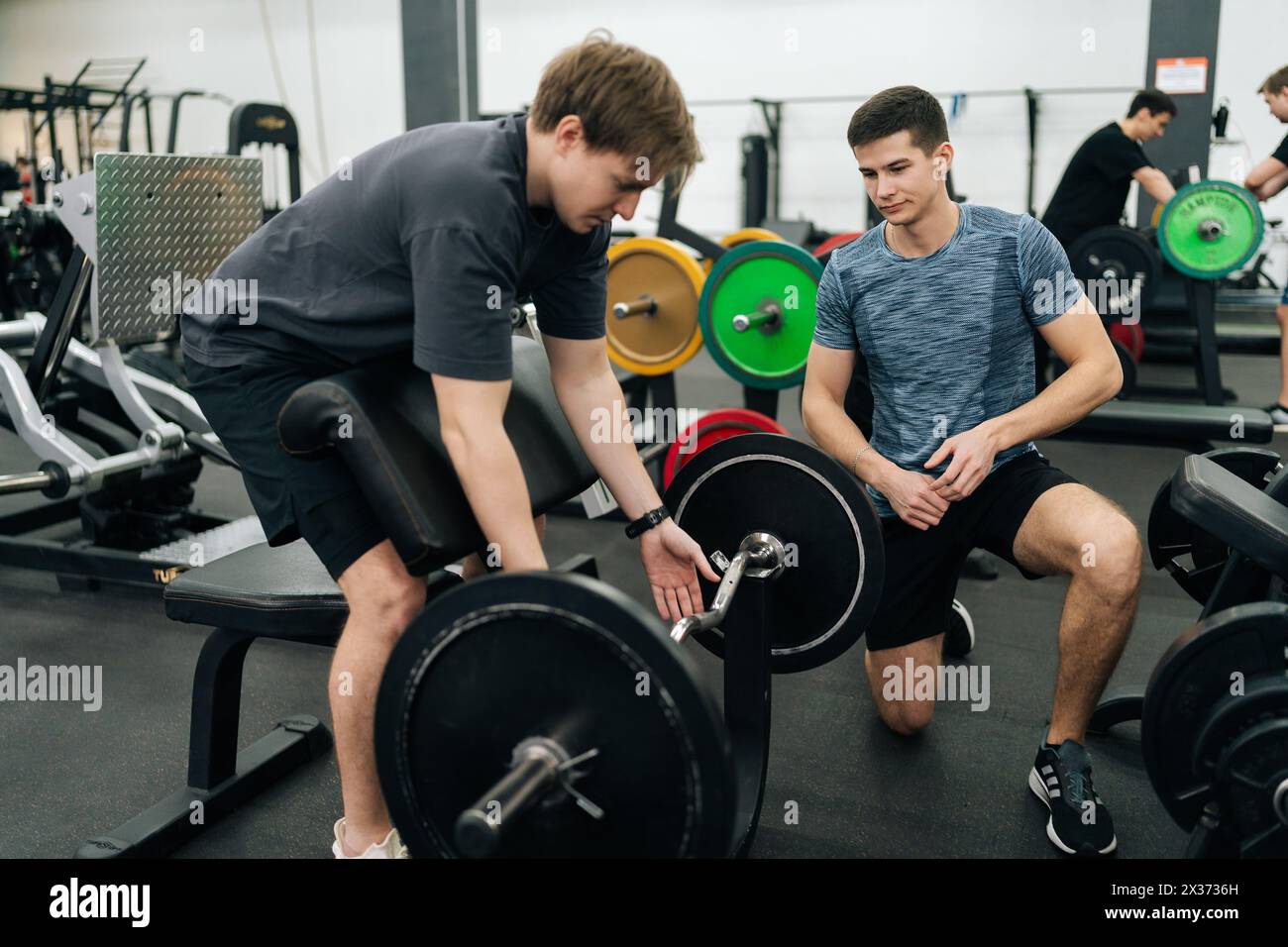 Side view of trainer helping beginner sportsman for correct doing Scott ...