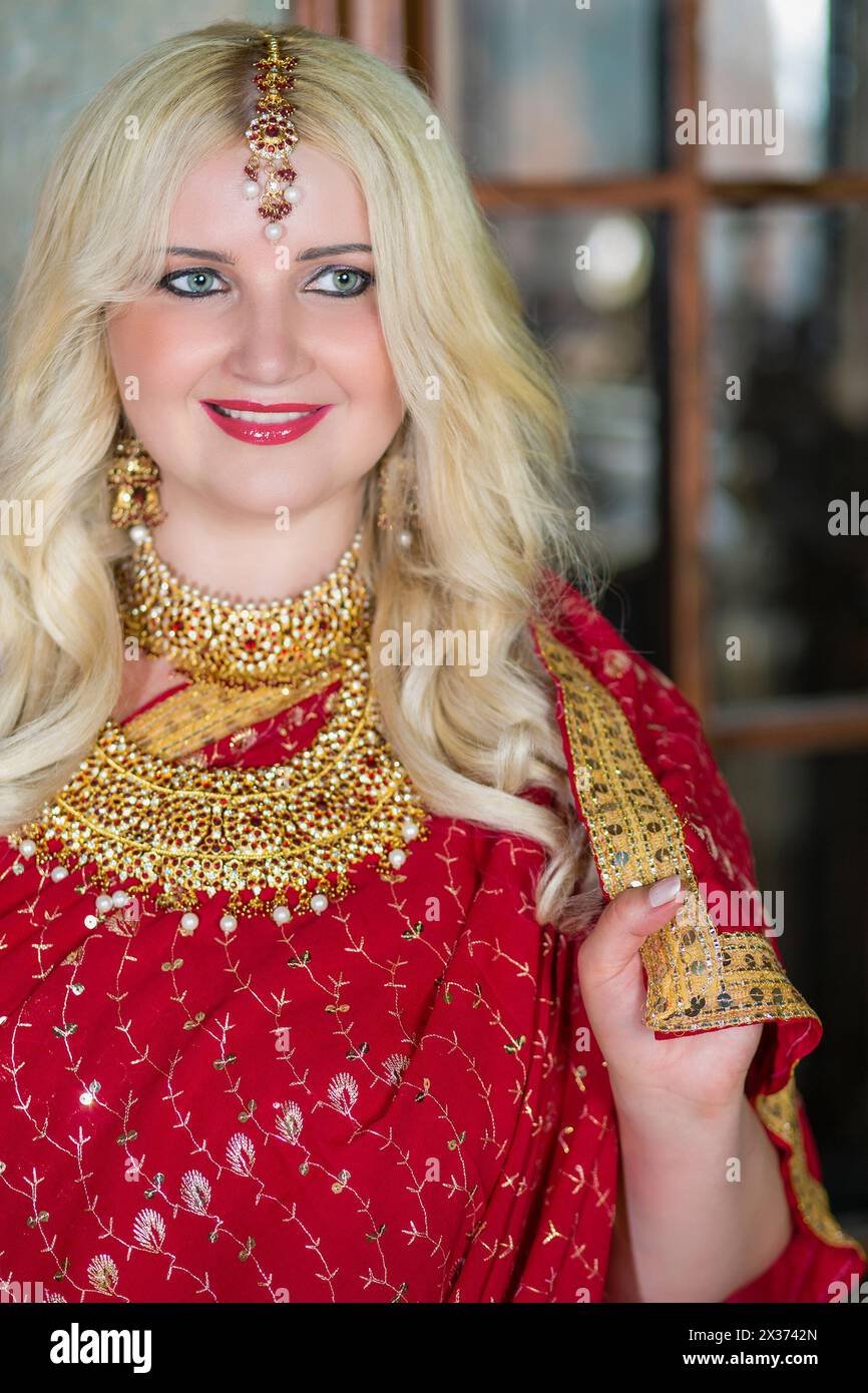 Smiling blonde woman in red dress and golden decorations Stock Photo ...