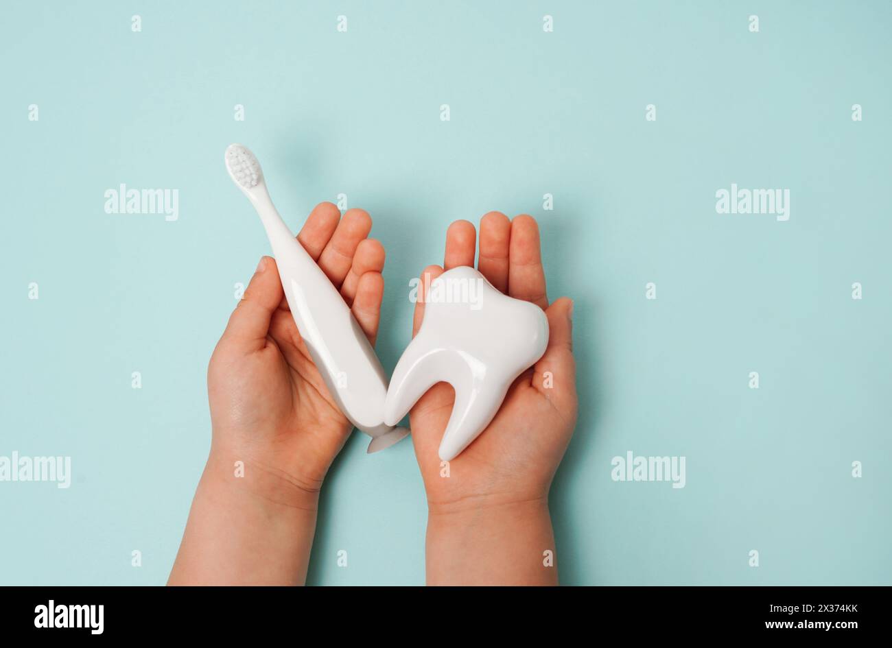 Child's hands holding big tooth and white toothbrush on blue background ...