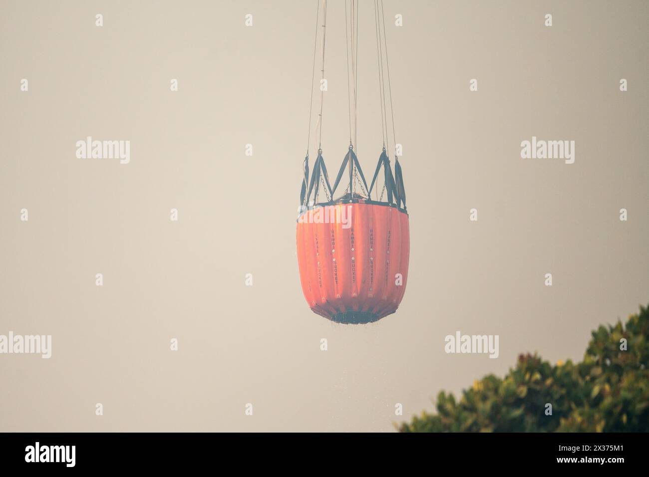 bambi bucket carrying water for aerial firefighting being winched up by ...